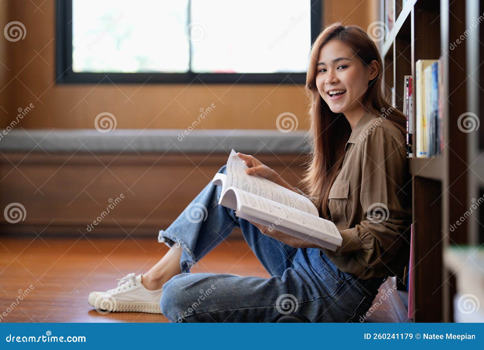 Portrait of a Happy Young Student Reading a Book in a Library Stock ...