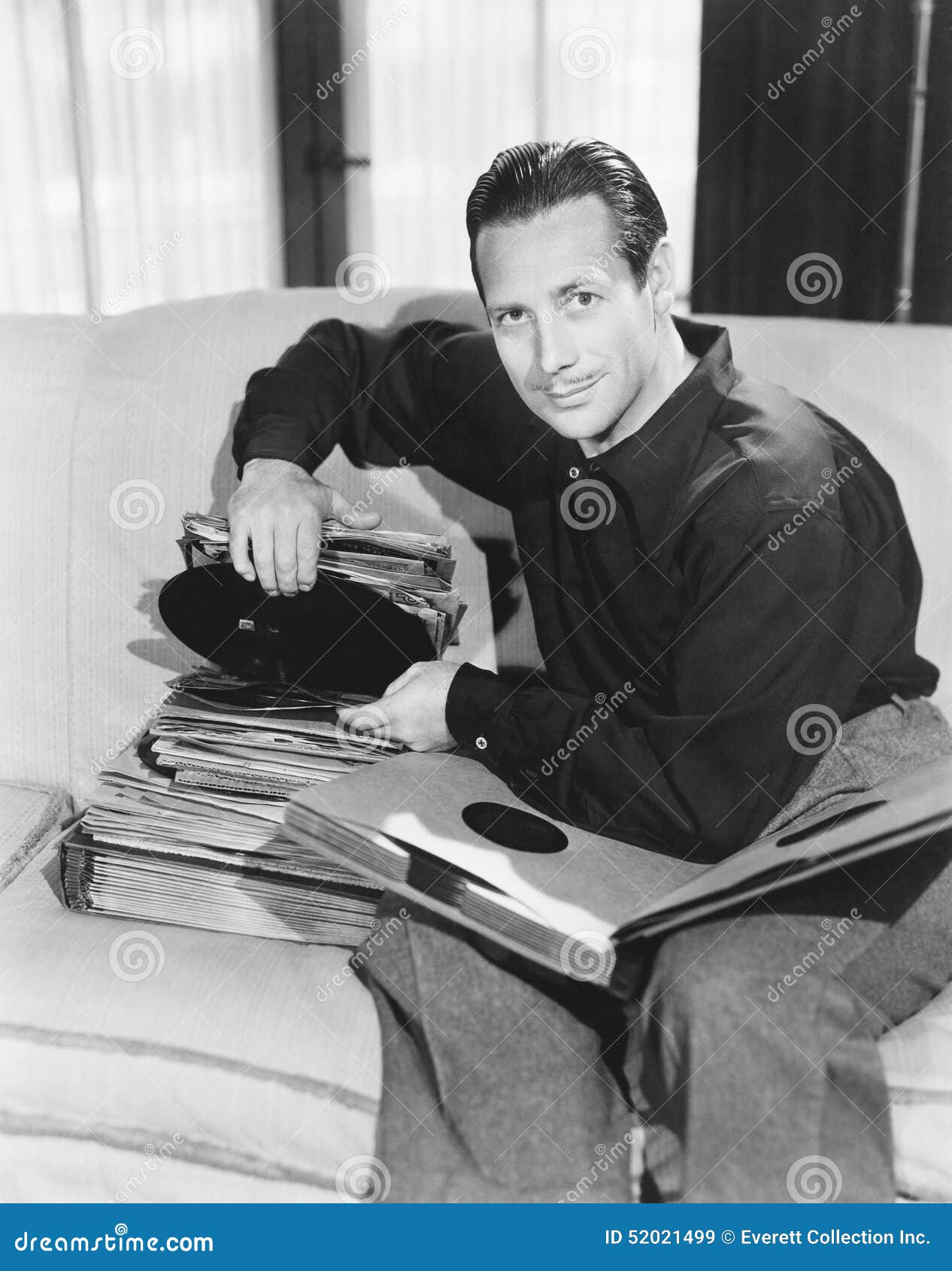 Portrait Of A Man Sitting On A Couch And Taking Out A Record From His ...
