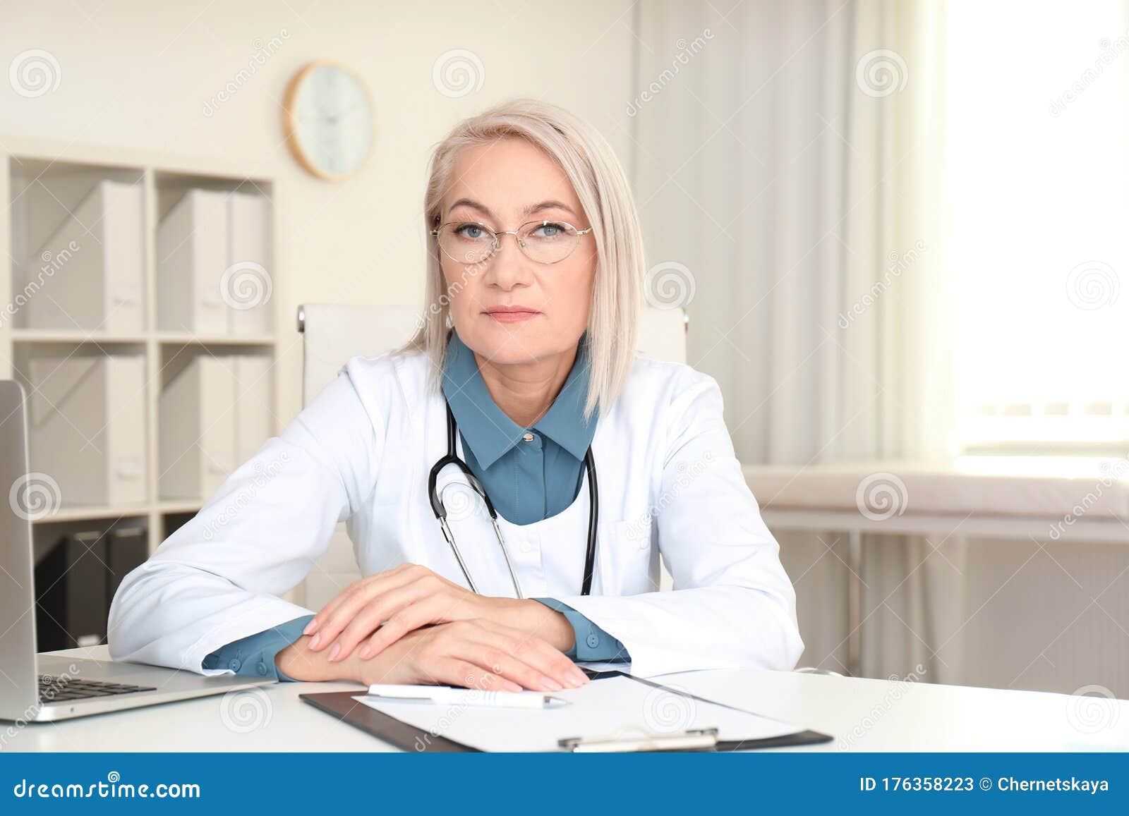 Portrait Of Mature Female Doctor In Coat At Workplace Stock Image