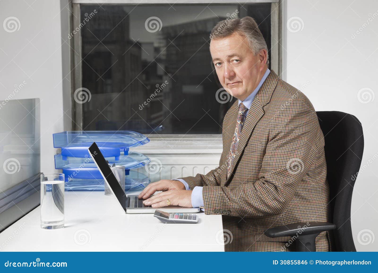 Portrait of Middle-aged Businessman Using Laptop at Desk in Office ...