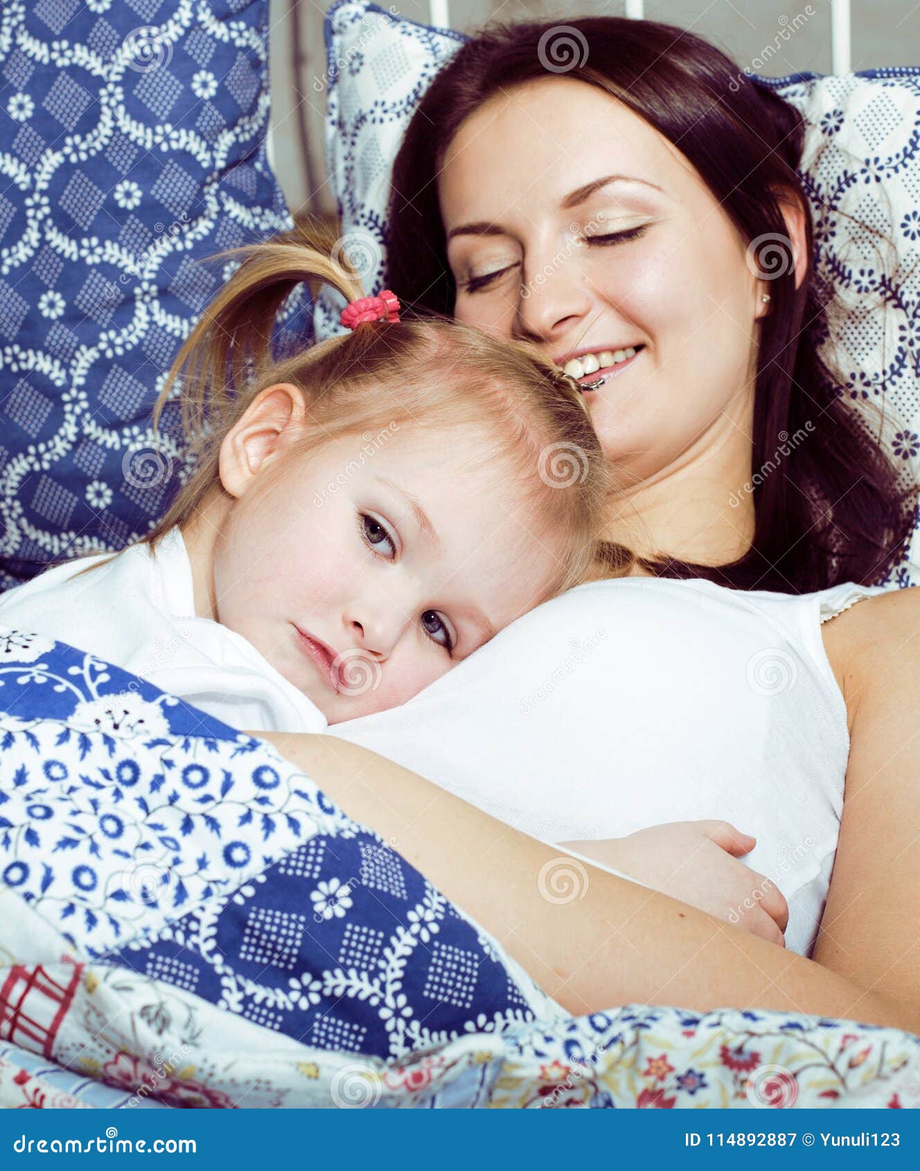 Portrait Of Mother And Daughter Laying In Bed And Smiling Close Stock