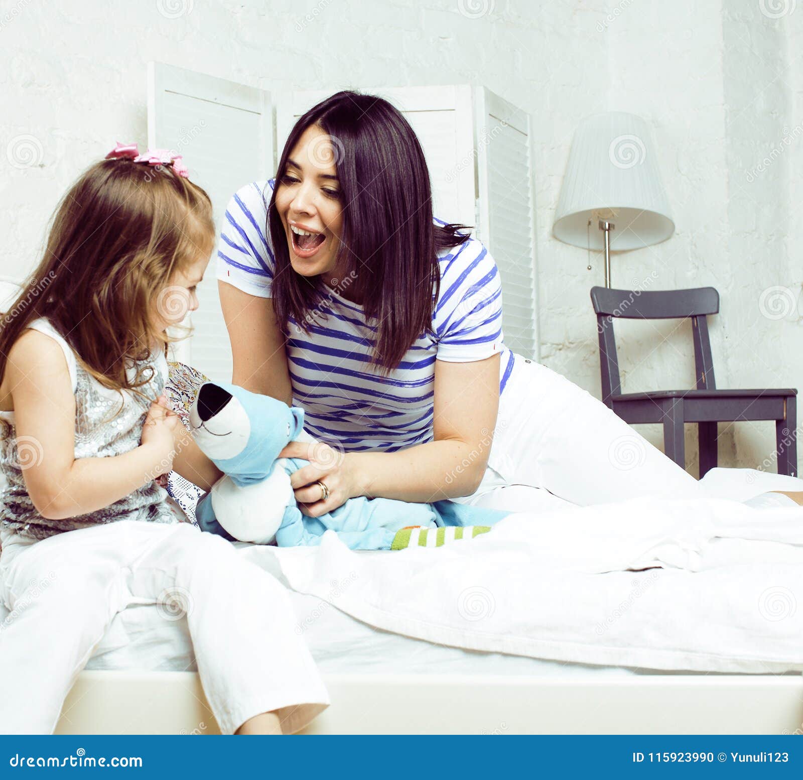 Portrait Of Mother And Daughter Laying In Bed And Smiling Close Stock