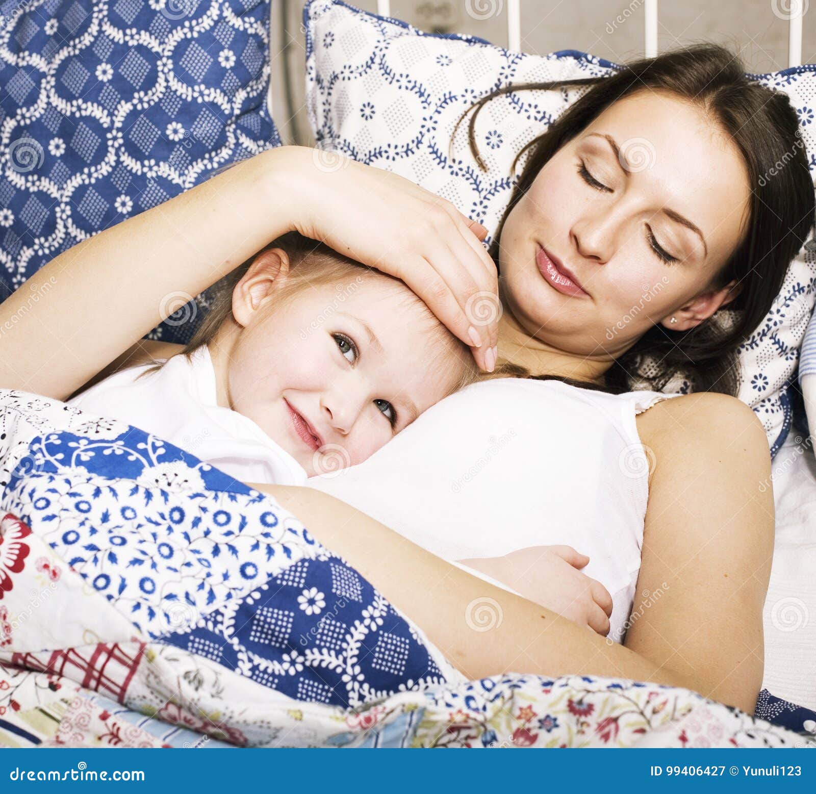 Portrait Of Mother And Daughter Laying In Bed And Smiling Stock Image