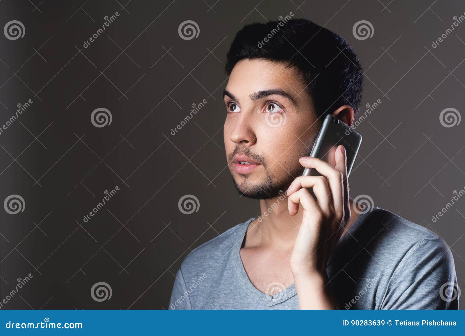 Portrait Of A Normal Boy Smiling Over Grey Background With Phone In ...