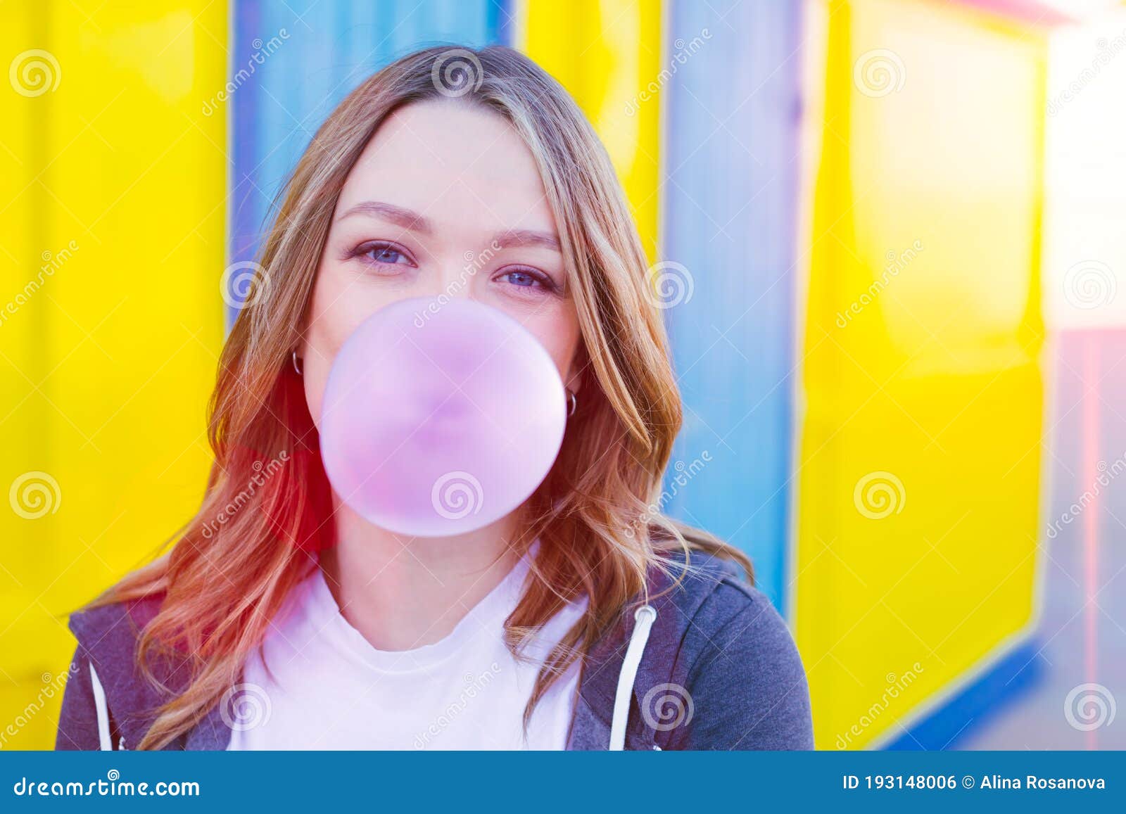 Portrait Of Playful Blonde Smiling Woman Blowing Bubble With Chewing