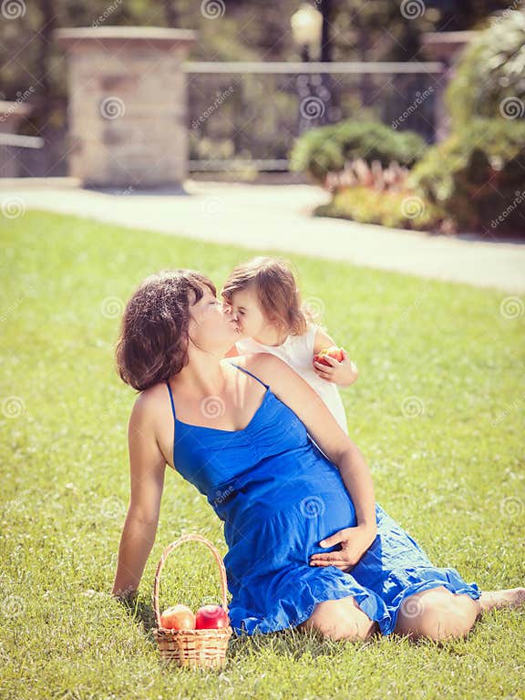 Portrait Of Pregnant Mother And Daughter Hugging Playing Outside Stock