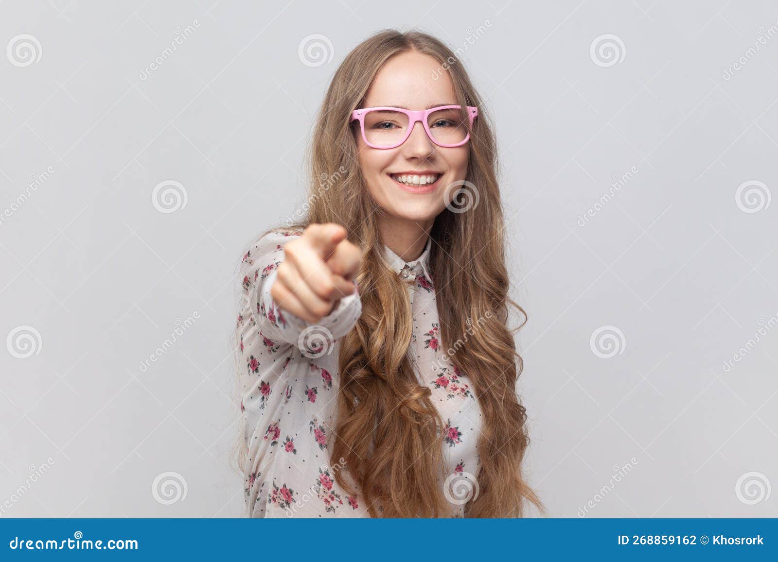 Pretty Cheerful Woman Looking At Camera With Toothy Smile Pointing