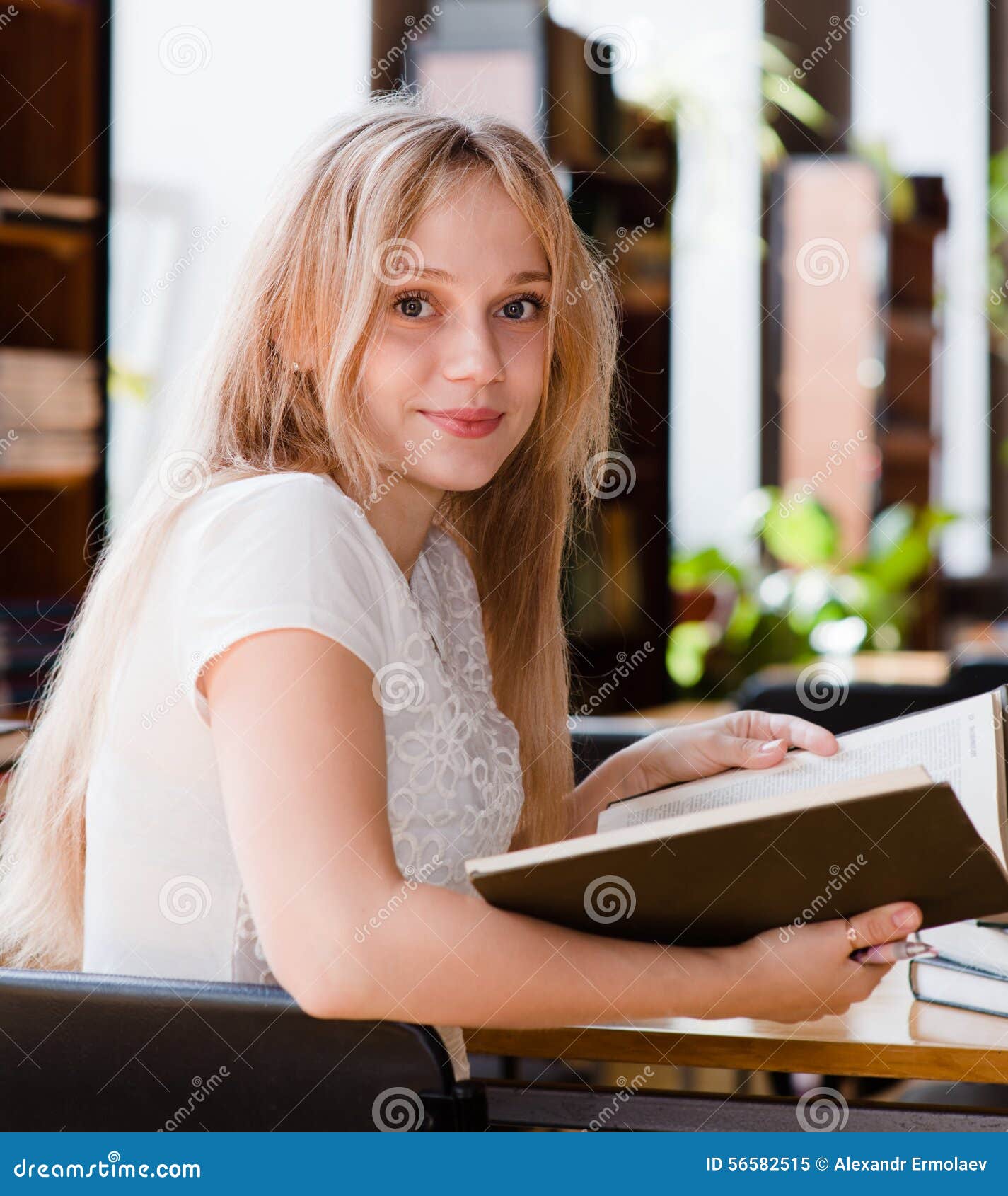 Portrait of a Pretty Female Student Studying in Library with Open Book ...