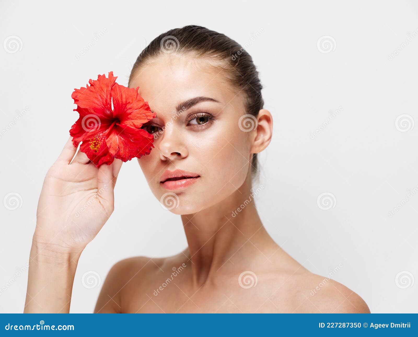 Portrait Of Pretty Woman With Red Flower Near Face On Light Background