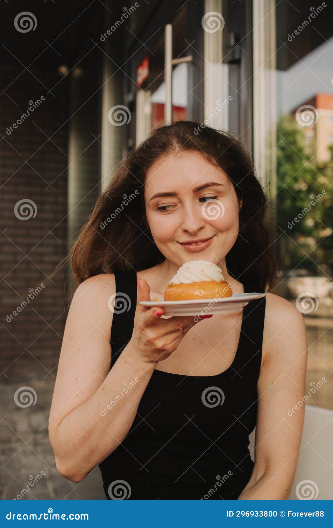 Portrait Of A Satisfied Woman Eating A Cake While Sitting At The Table