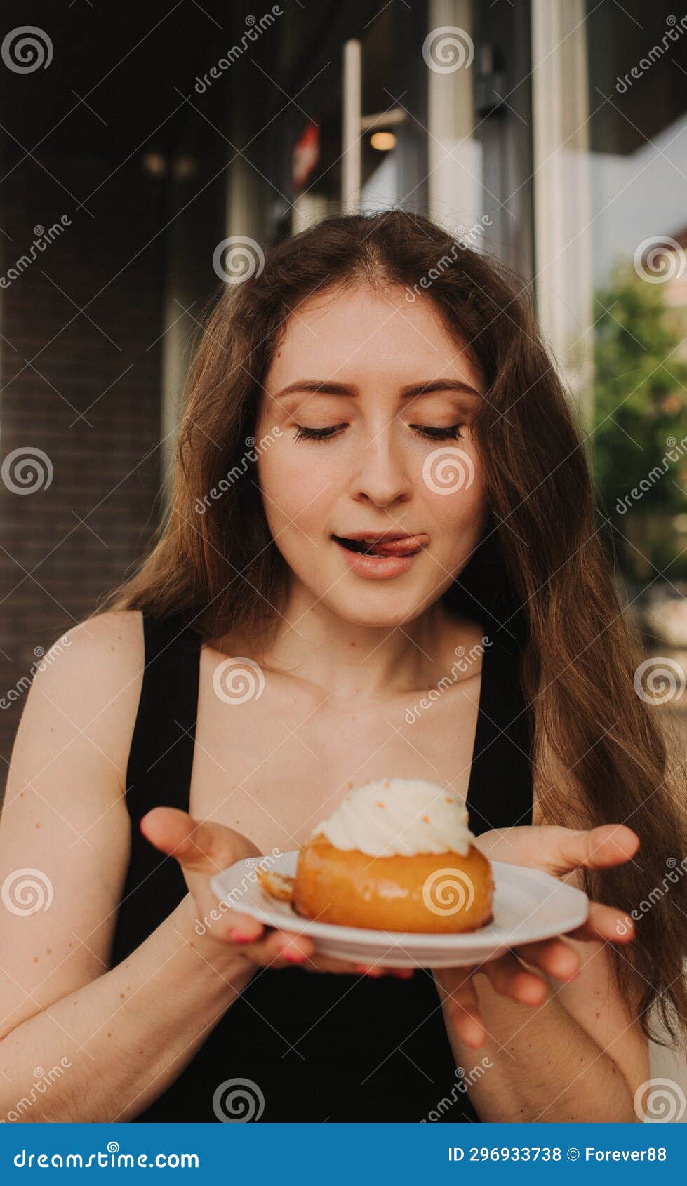 Portrait Of A Satisfied Woman Eating A Cake While Sitting At The Table
