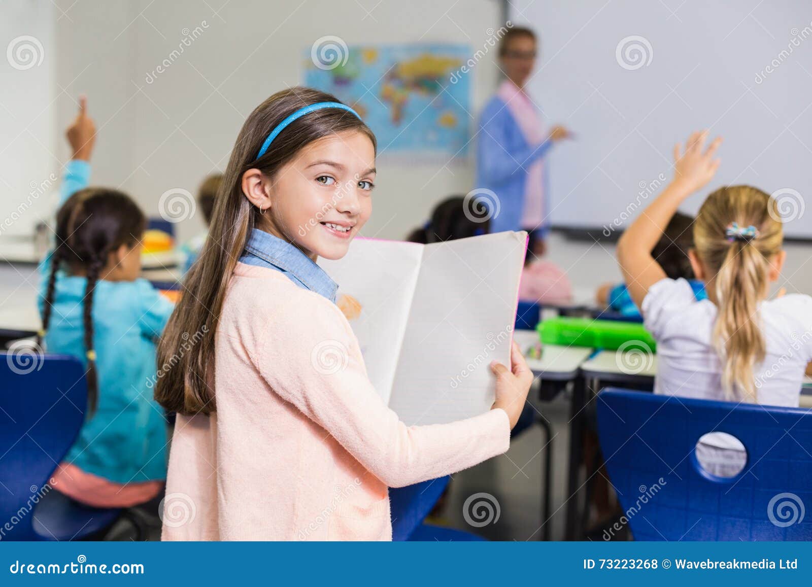 Portrait of Schoolgirl Standing with Book in Classroom Stock Photo ...