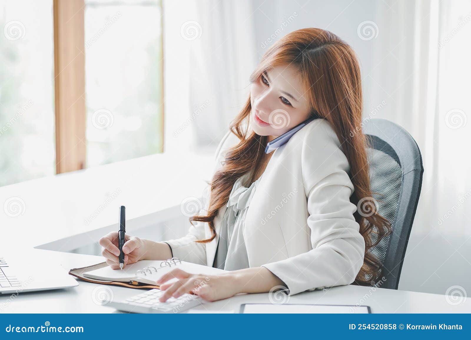 Portrait of Secretary Writing on a Notepad and Talking on Telephone ...