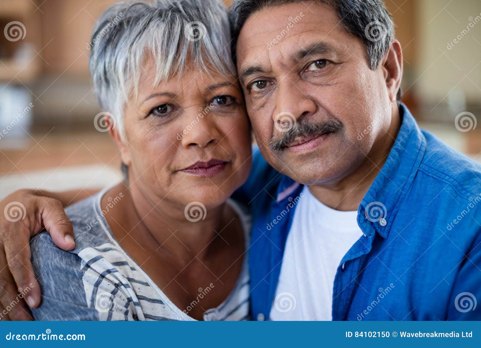 Portrait Of Senior Couple Embracing Each Other In Living Room Stock