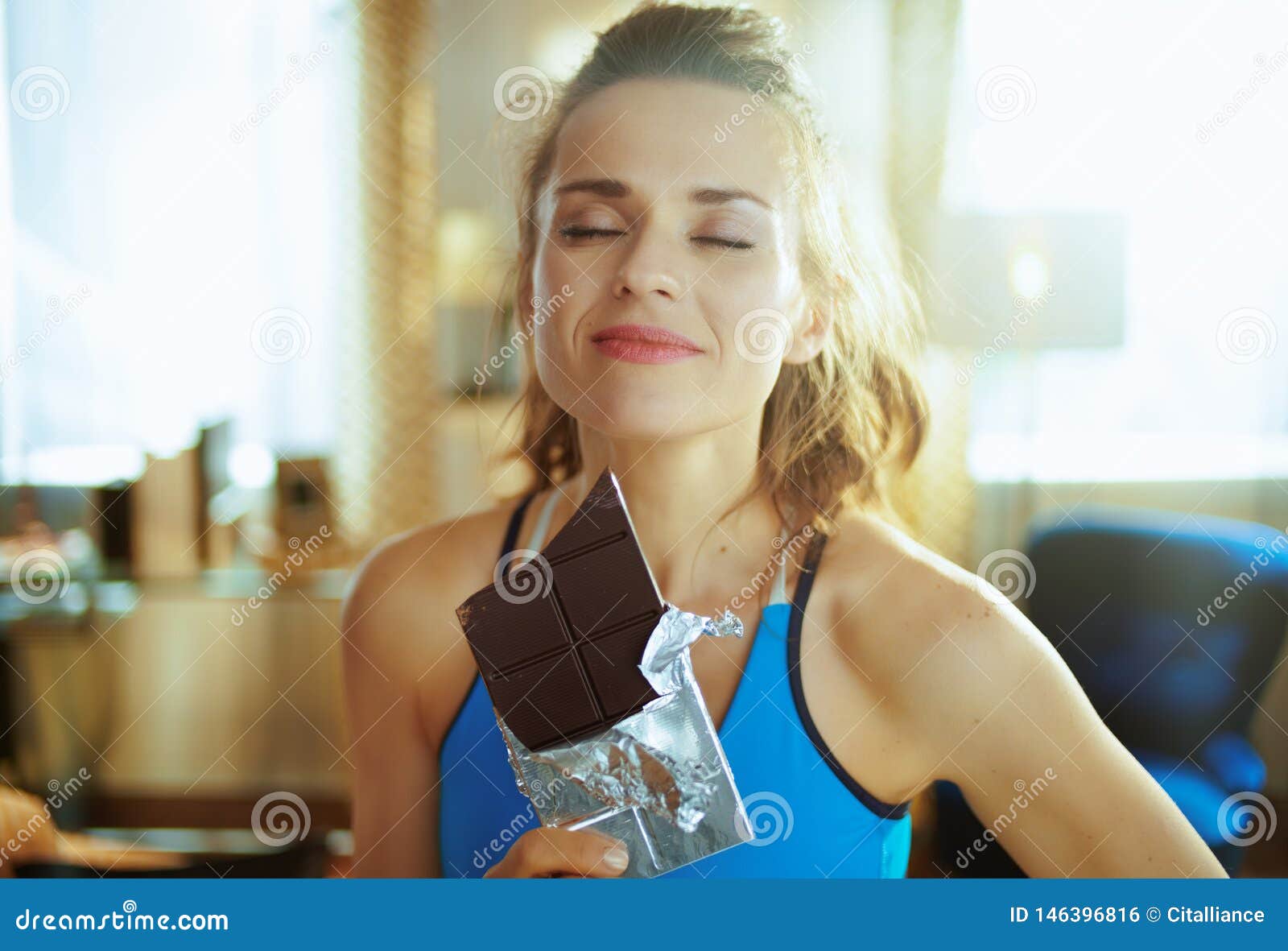 Smiling Sports Woman in Modern House Enjoying Chocolate Bar Stock Photo ... Smiling Sports Woman in Modern House Enjoying Chocolate Bar Stock Photo ...