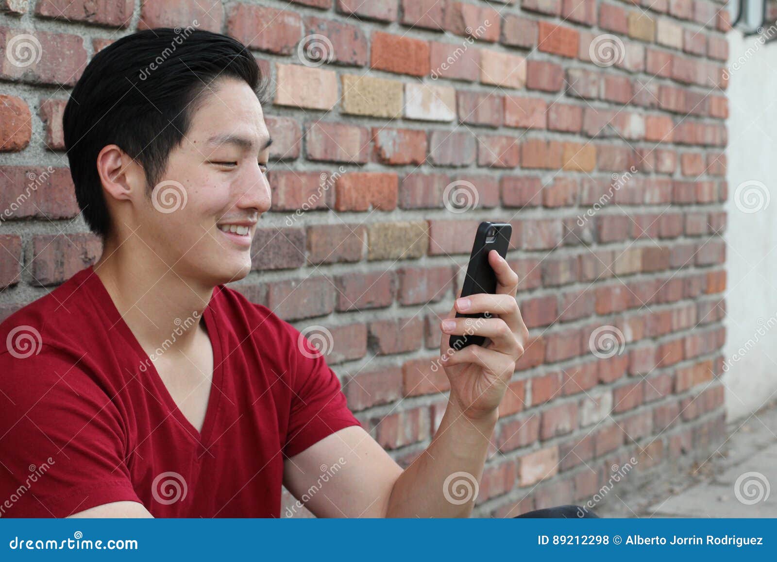 Portrait of a Smiling Asian Guy Texting on Mobile Phone Outside Stock ...