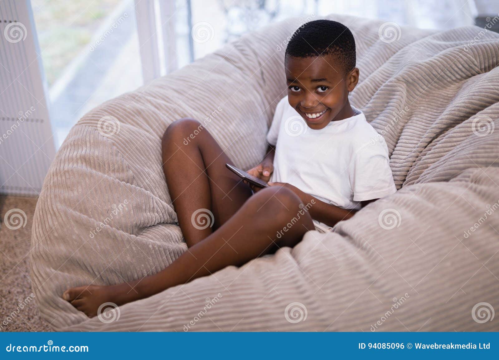 Portrait of Smiling Boy Using Mobile Phone while Sitting on Couch at ...