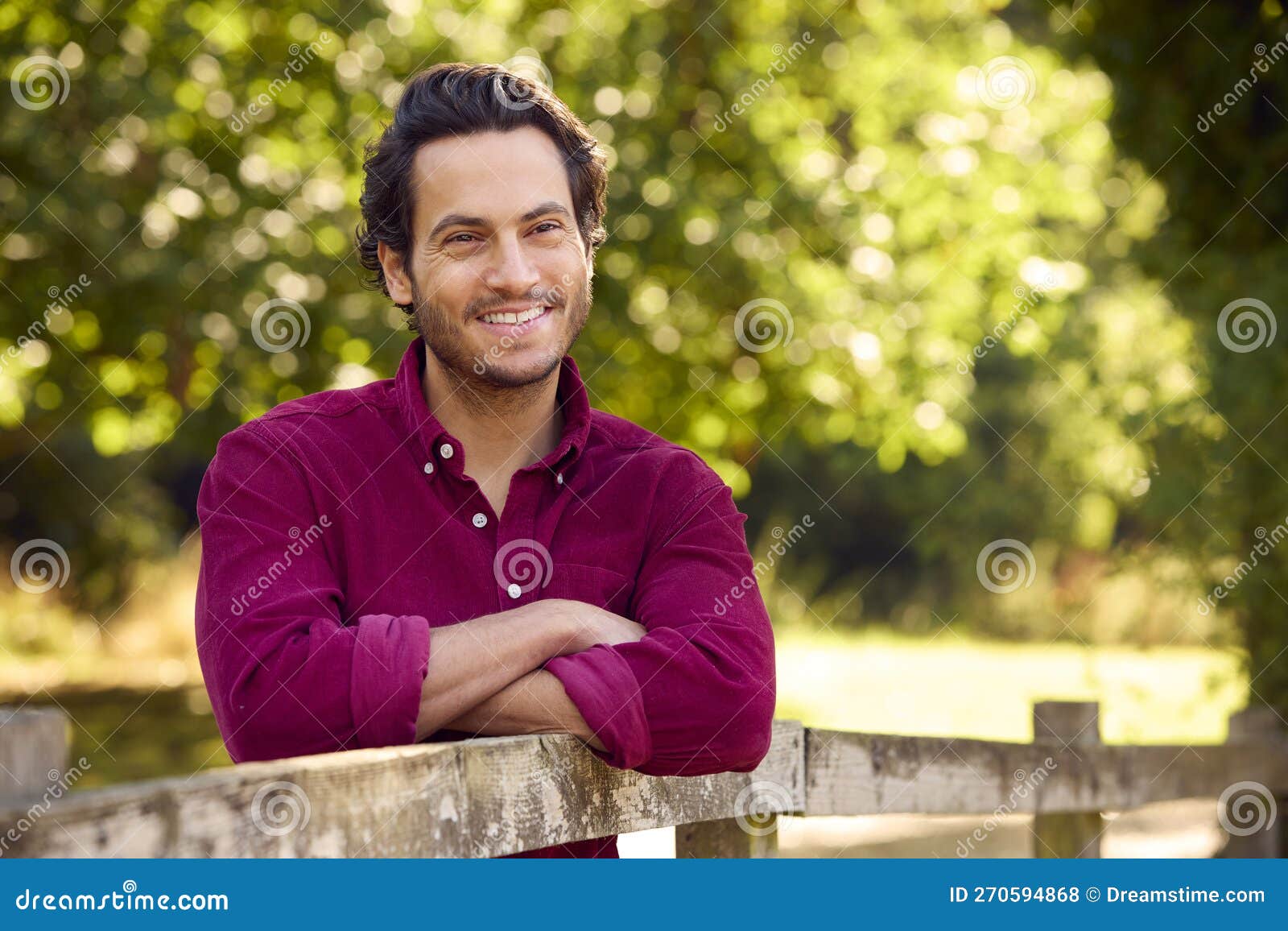 Portrait Of Smiling Casually Dressed Mature Man Leaning On Fence On