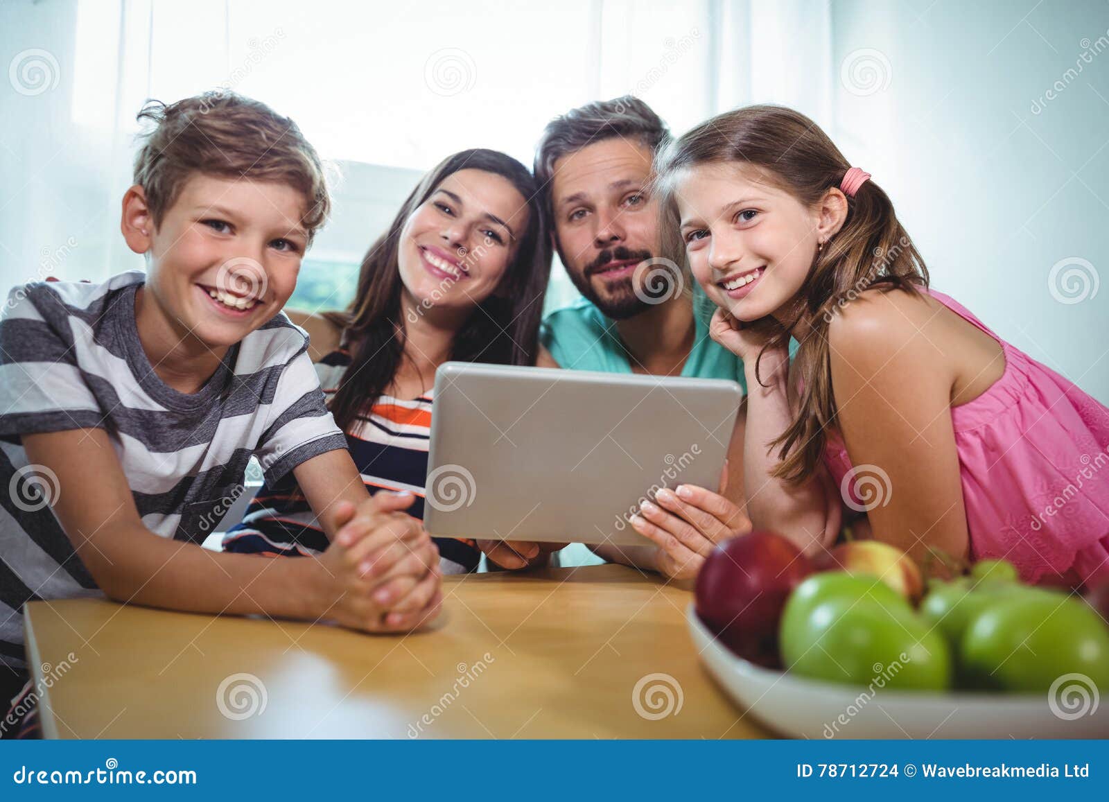 Portrait of Smiling Family Using Digital Tablet while Sitting at Table ...