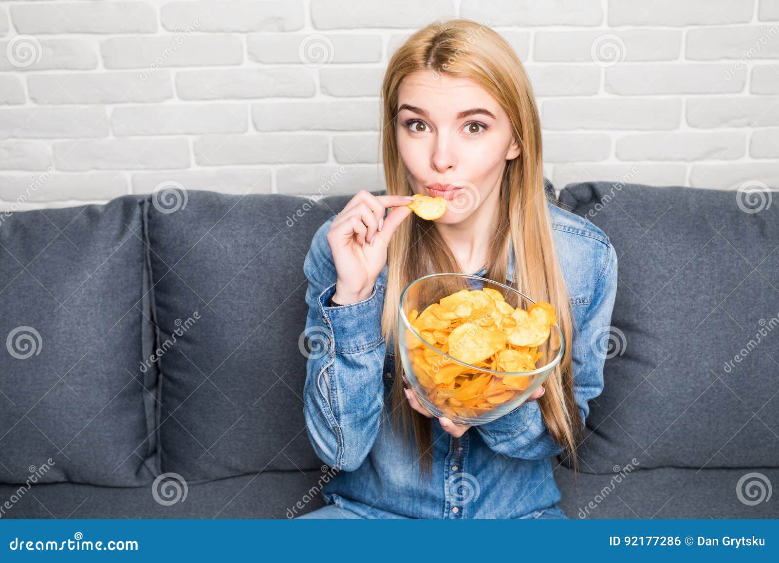 Portrait of Smiling Girl Eating Chips at Home on Sofa Stock Photo ...
