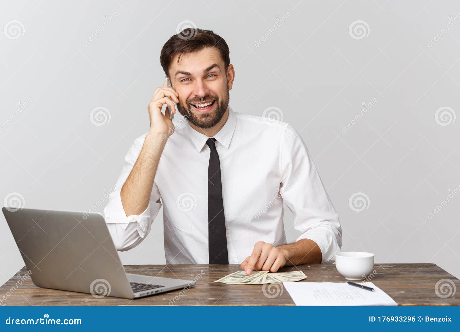 Portrait of Smiling Man Speaking on Mobile Phone, Sitting at Desk ...