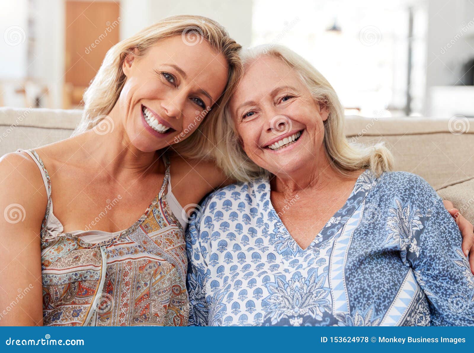 Portrait Of Smiling Mother With Adult Daughter Relaxing On Sofa At Home