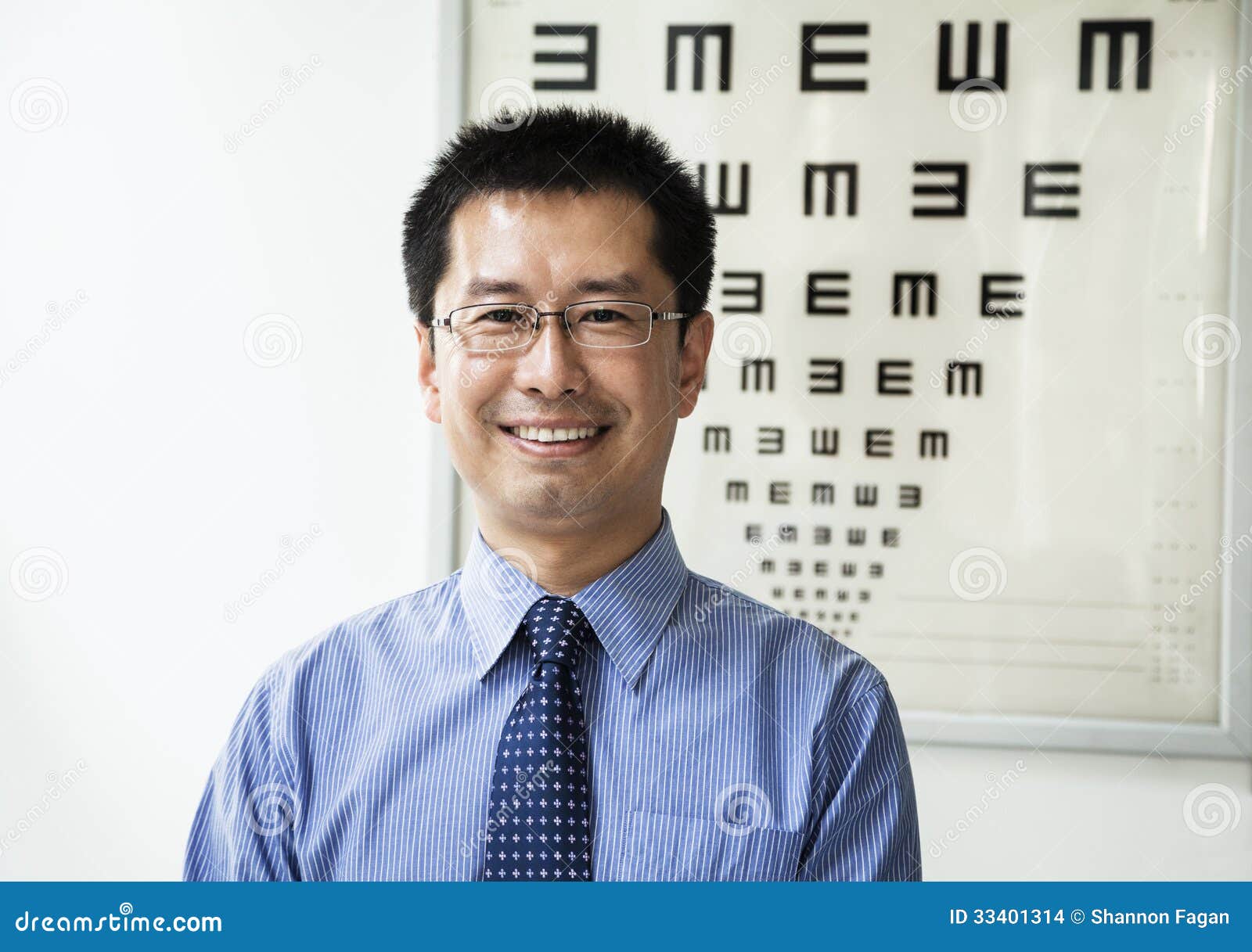 Portrait Of Smiling Optometrist With An Eye Chart In The Background ...