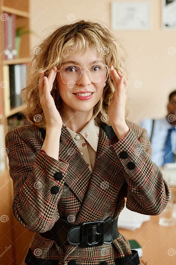 Portrait Of Smiling Woman Adjusting Her Glasses Indoors Stock Image