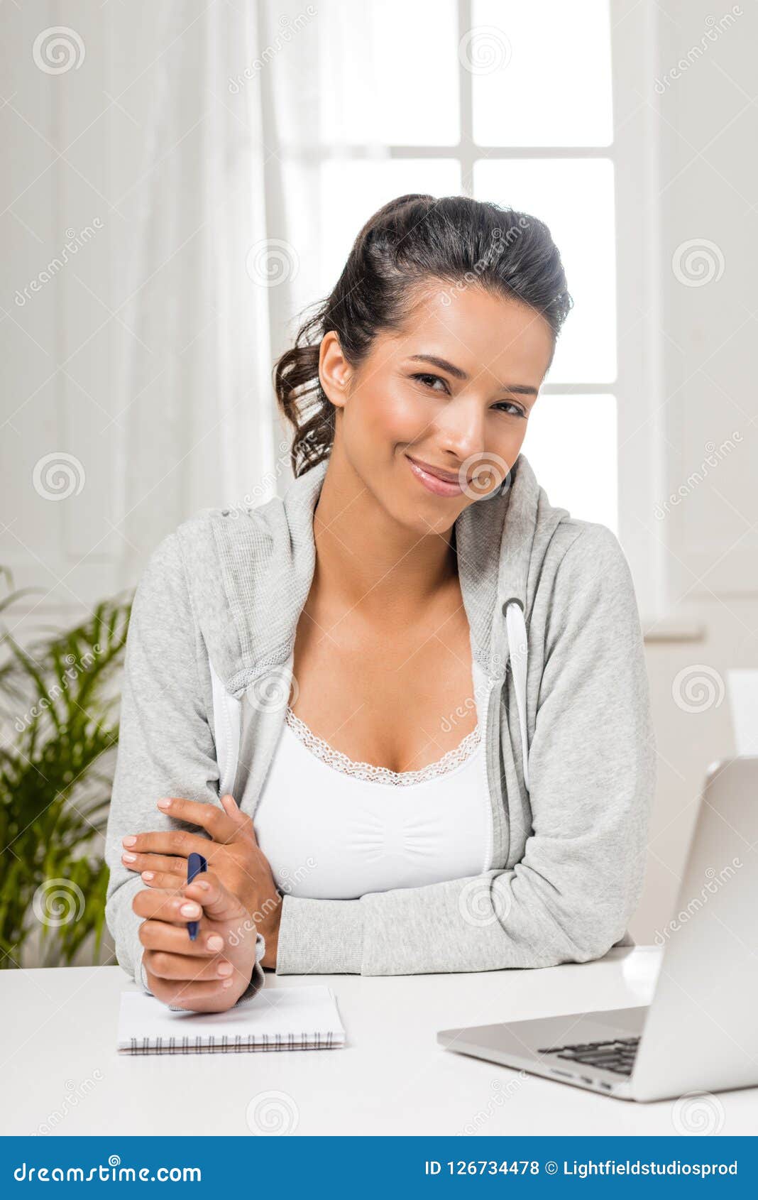 Portrait Of Smiling Woman Looking At Camera While Sitting At Workplace