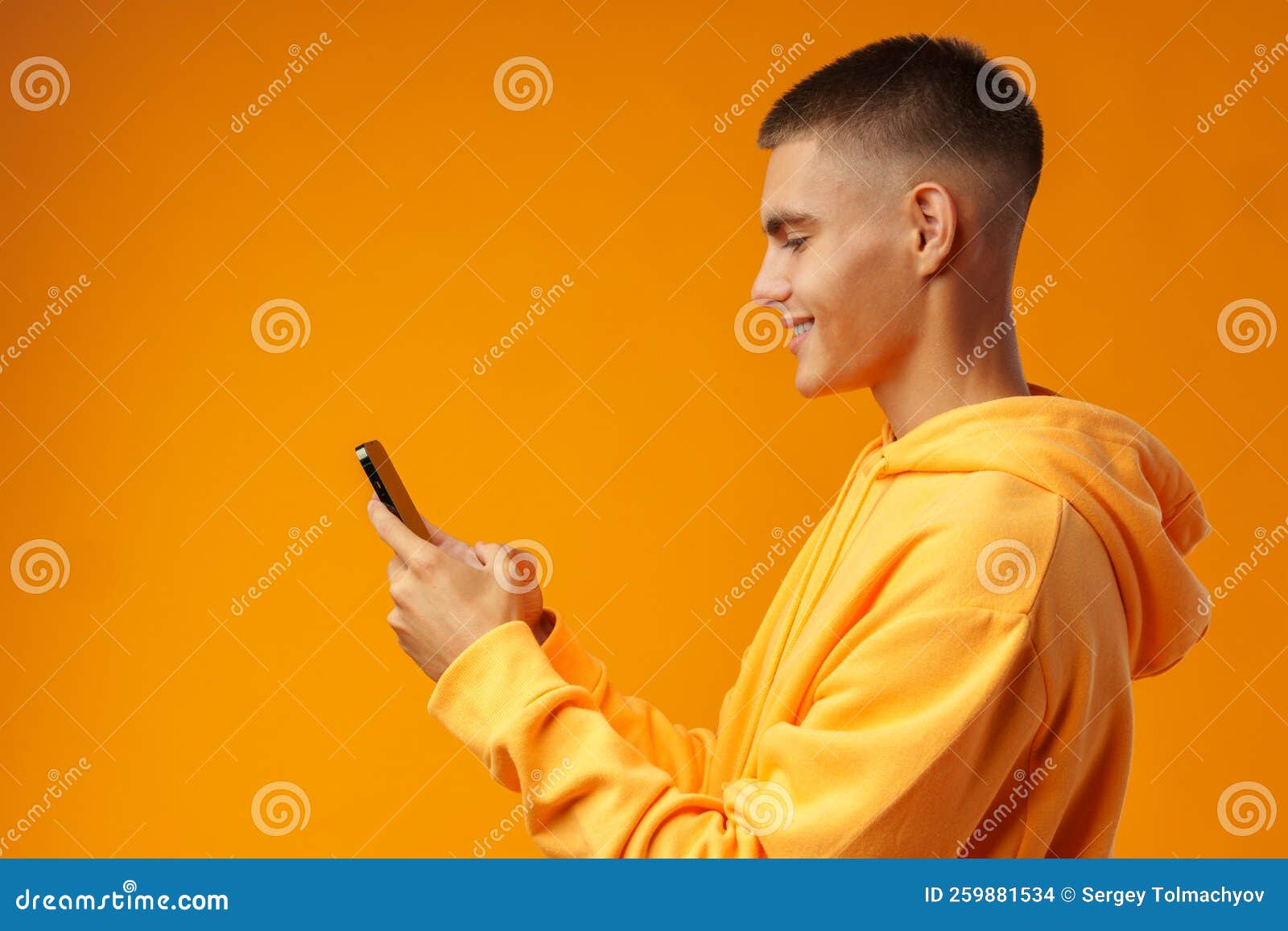 Portrait of a Smiling Young Man Holding Mobile Phone on Yellow ... Portrait of a Smiling Young Man Holding Mobile Phone on Yellow ...