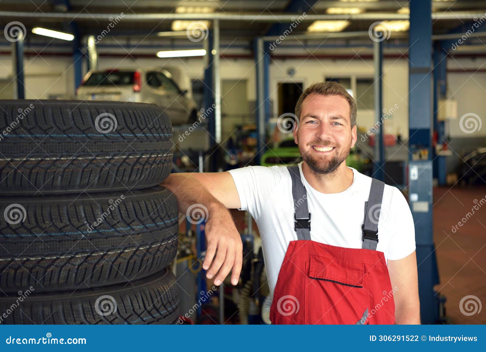 Portrait of Successful Smiling Car Mechanic in a Workshop on a Stack of ...