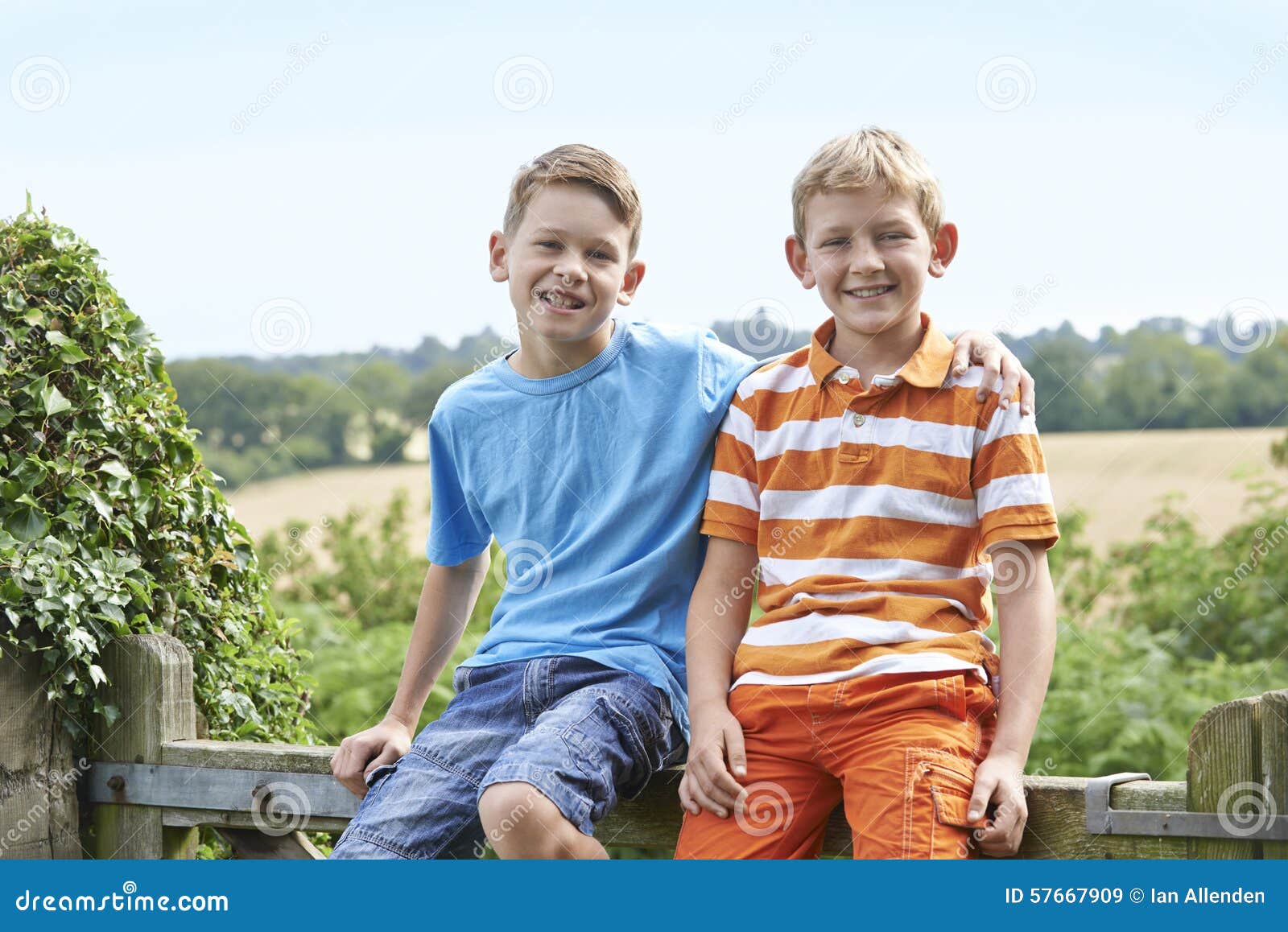 Portrait of Two Boys Sitting on Gate Together Stock Image - Image of ...