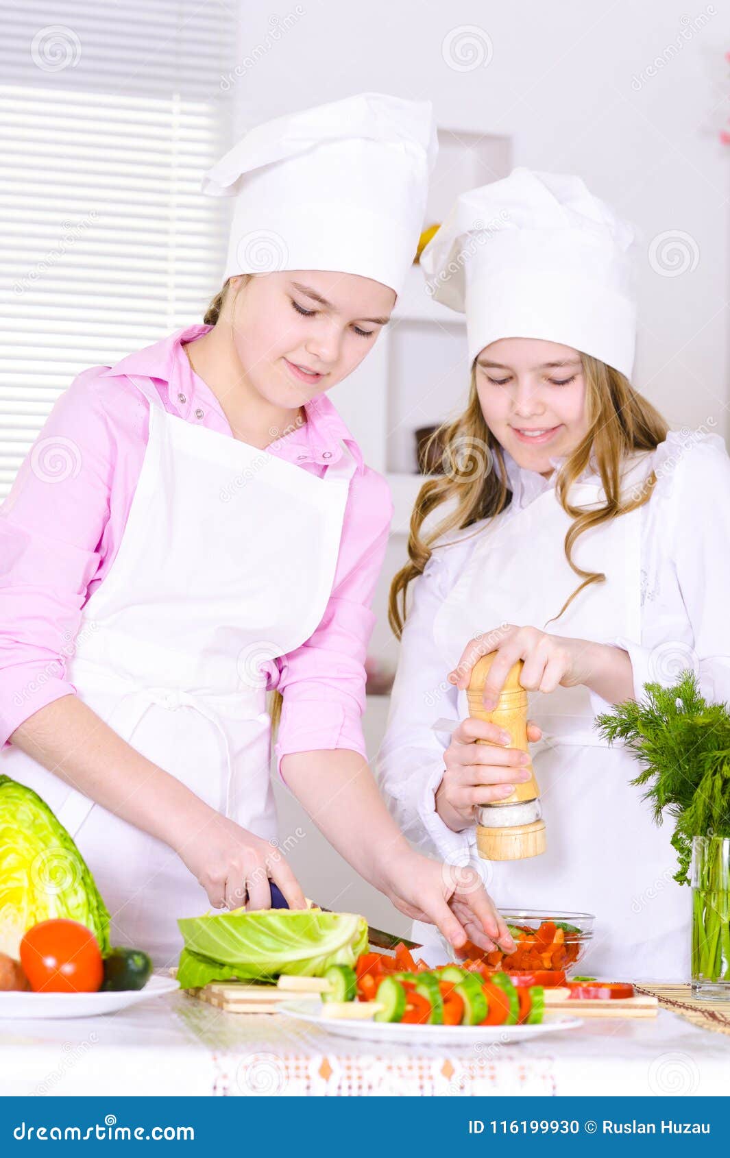 Two cute girls cooking stock photo. Image of peppers - 116199930