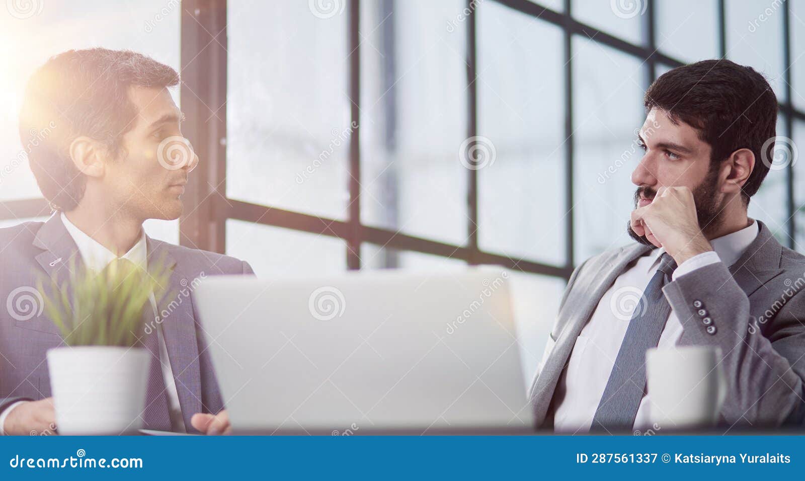 Portrait of Two Diverse Colleagues Sitting at Desk and Using Laptop ...
