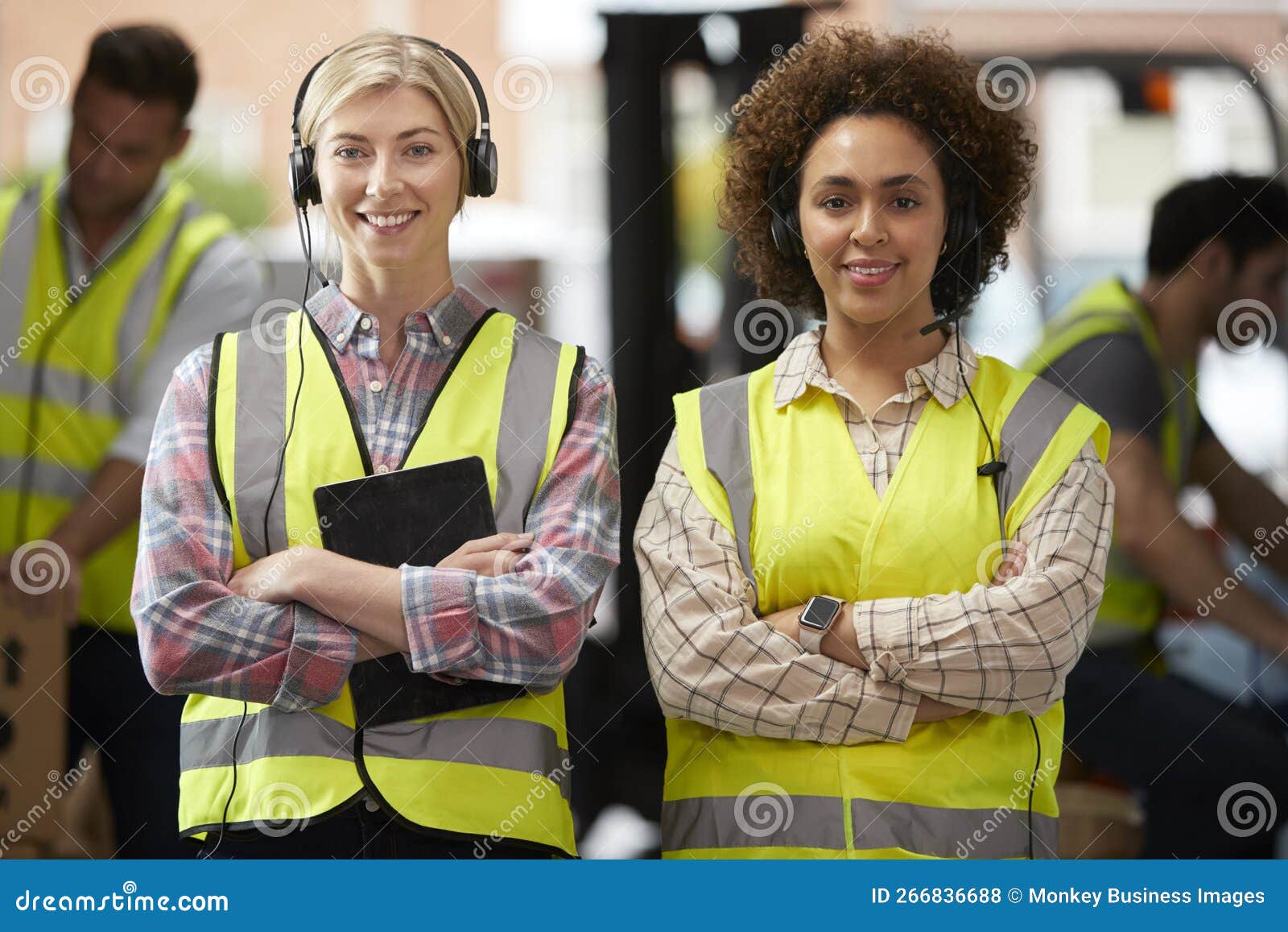 Portrait of Two Female Workers Using Headsets in Distribution Warehouse ...