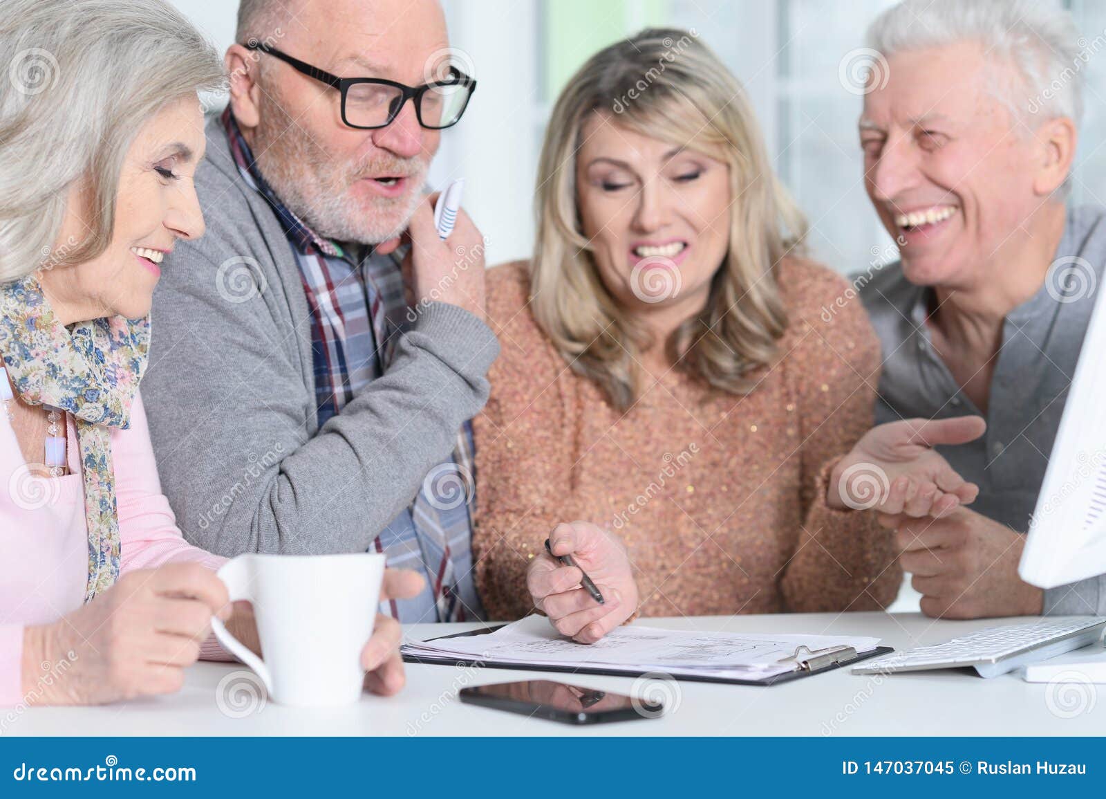 Portrait of Two Senior Couples Sitting at Table and Working Stock Image ...