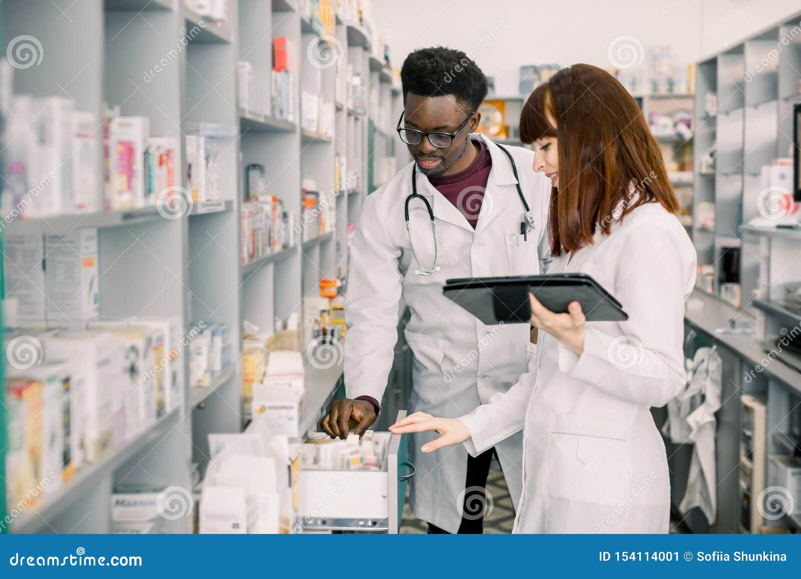 Portrait of Two Smiling Friendly Multiethnical Pharmacists Working in ...