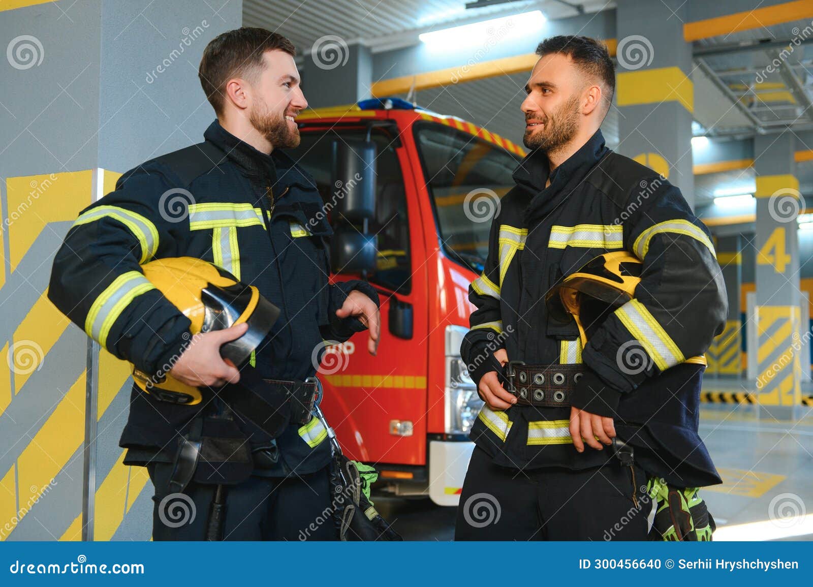 Portrait of Two Young Firemen in Uniform Standing Inside the Fire ...