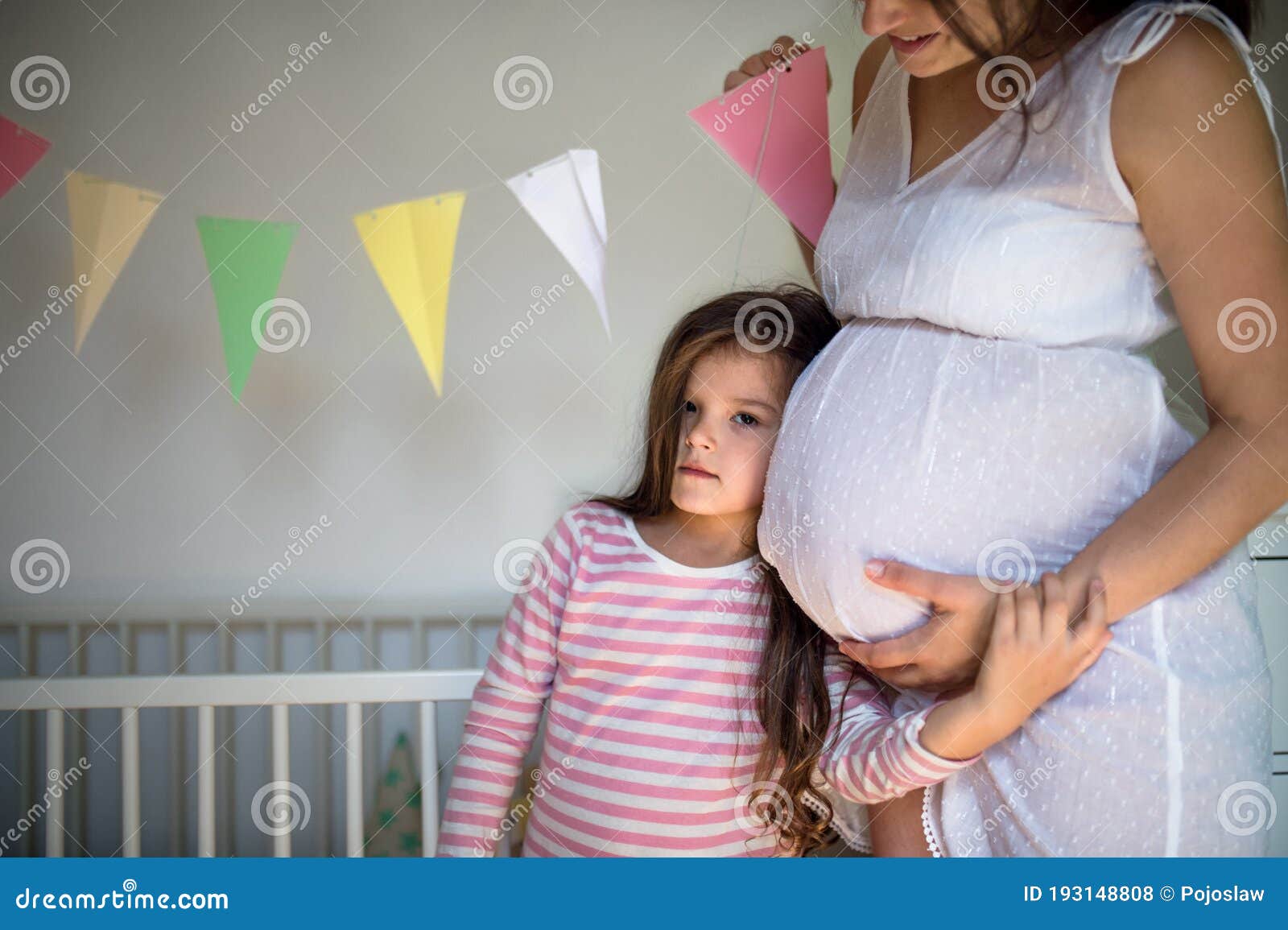Portrait Of Happy Pregnant Woman With Small Daughter Indoors At Home