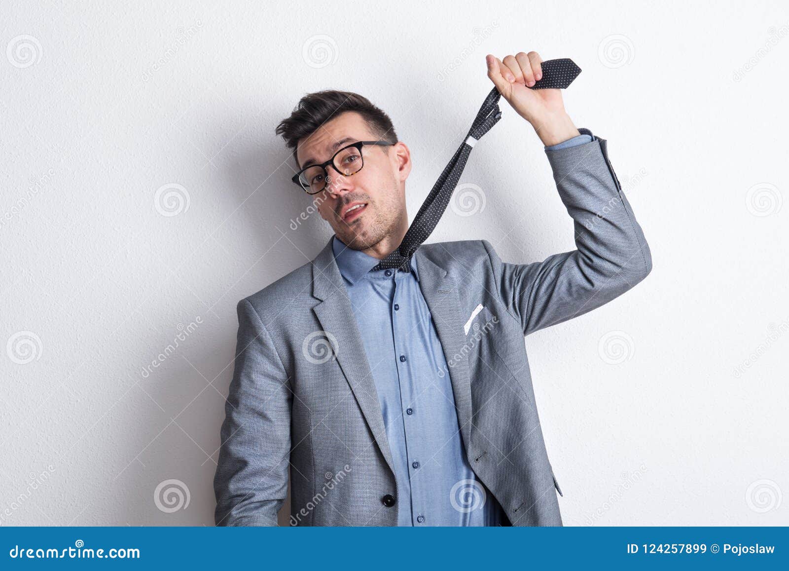 A Worried Young Businessman Holding Up a Tie in a Studio. Stock Image ... A Worried Young Businessman Holding Up a Tie in a Studio. Stock Image ...