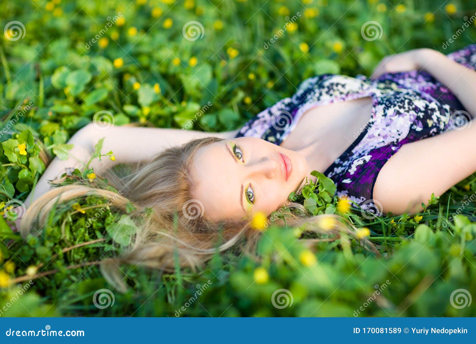 Portrait Of Young Beautiful Blond Woman Lying In Grass And Flowers On