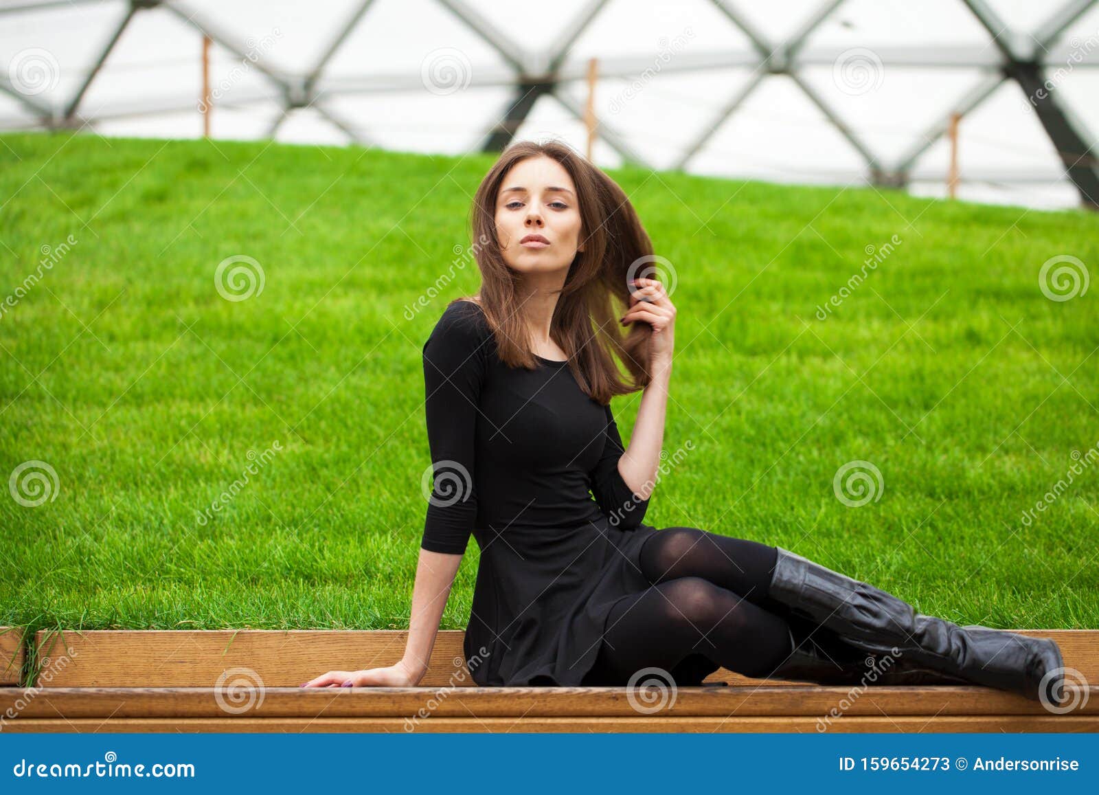 Portrait Of A Young Beautiful Woman In A Black Dress Sitting On The