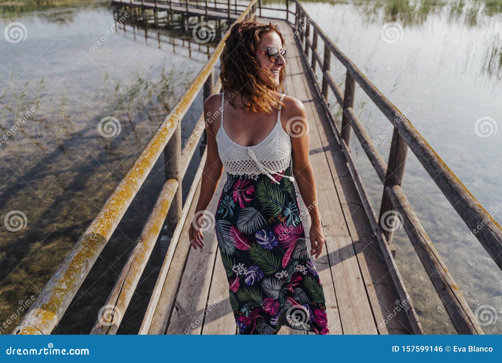 Portrait Of Young Beautiful Woman Standing On A Wood Pier In A Natural