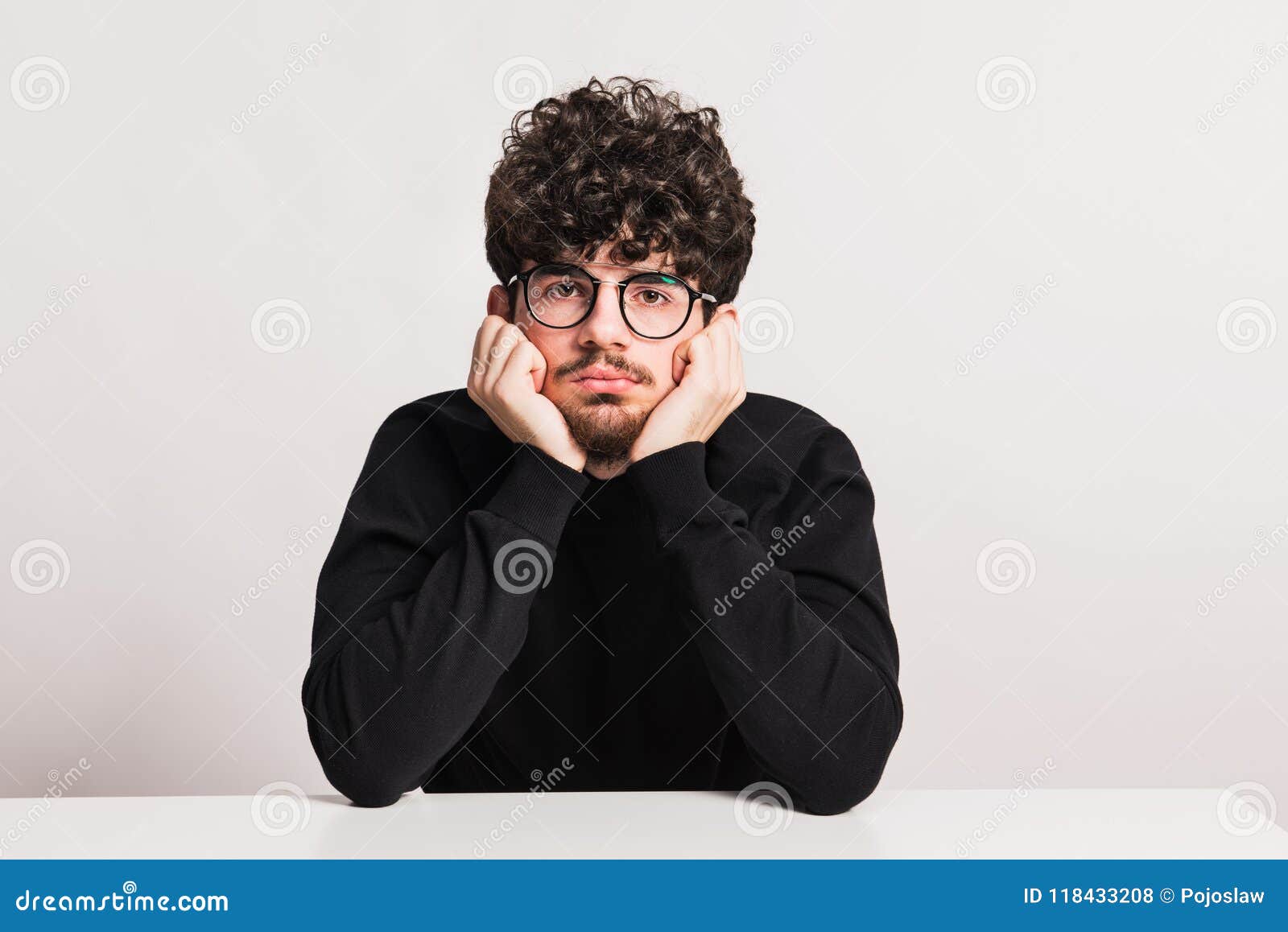 Young Bored Man in a Studio, Sitting at the Table. Stock Photo - Image ...