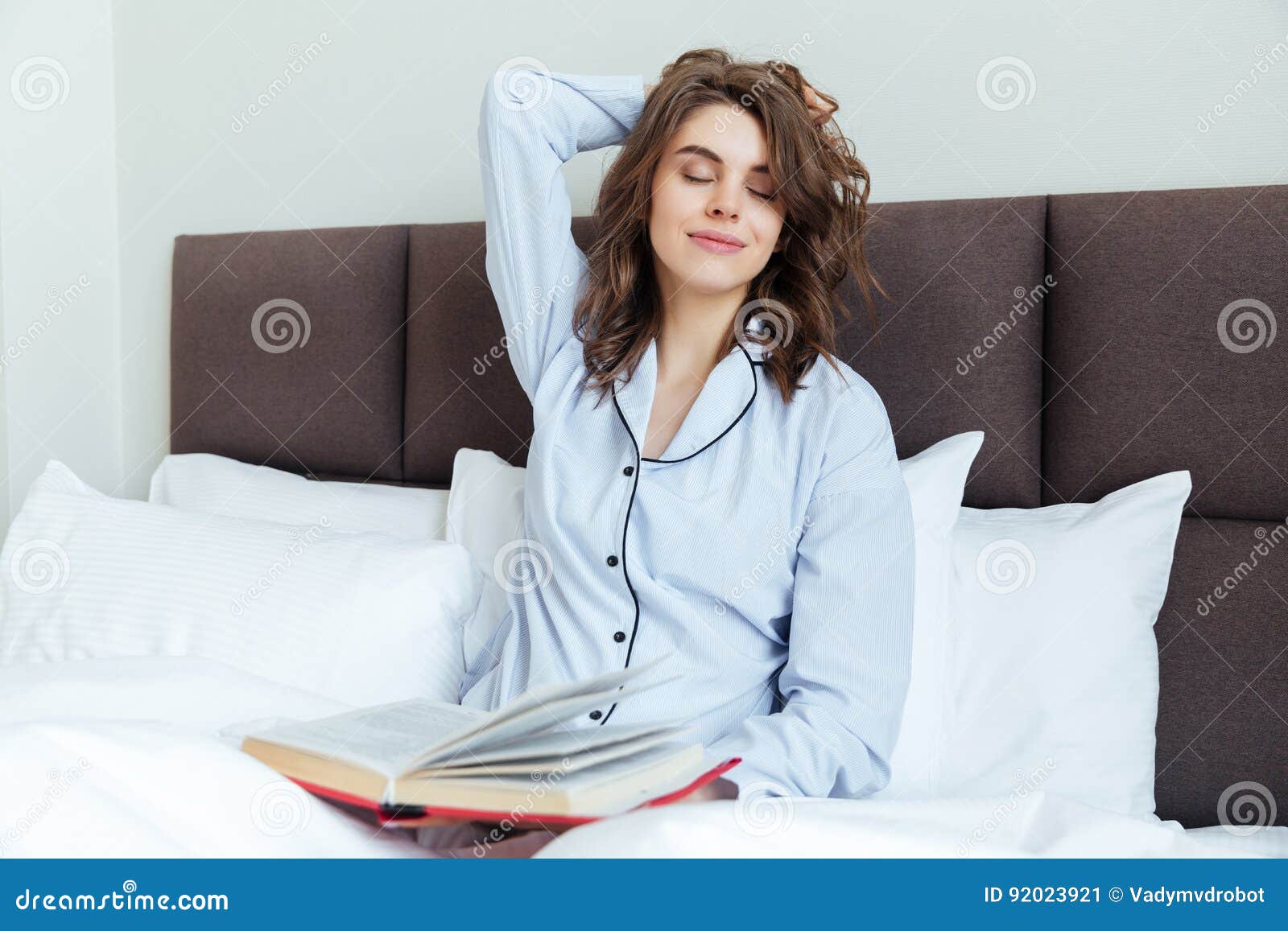 Portrait Of A Young Brunette Woman In Pajamas Reading Book Stock Image