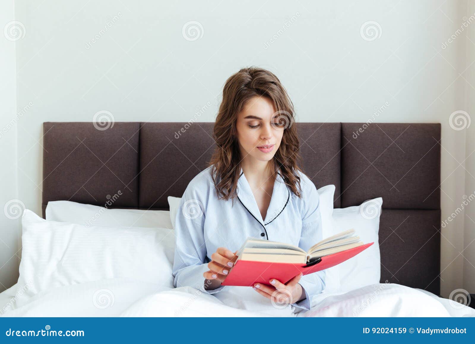Portrait Of A Young Brunette Woman In Pajamas Reading Book Stock Image