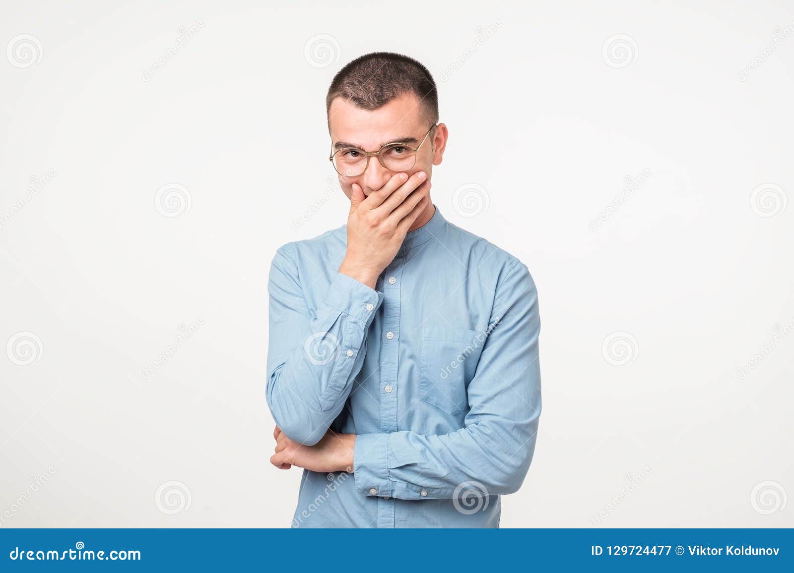 Portrait Of Young Man Laughing And Covering His Mouth With Hand Over