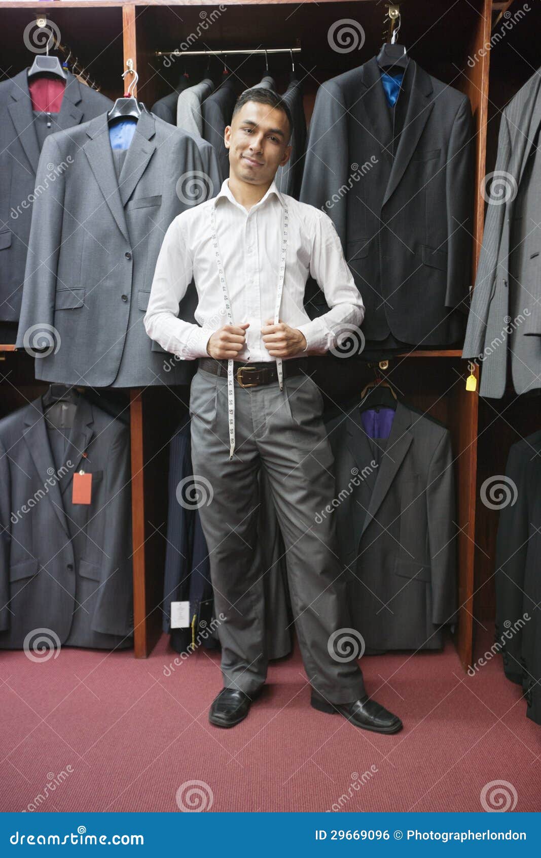 Portrait of Young Man Posing with Suits Hanging in Background Stock ...