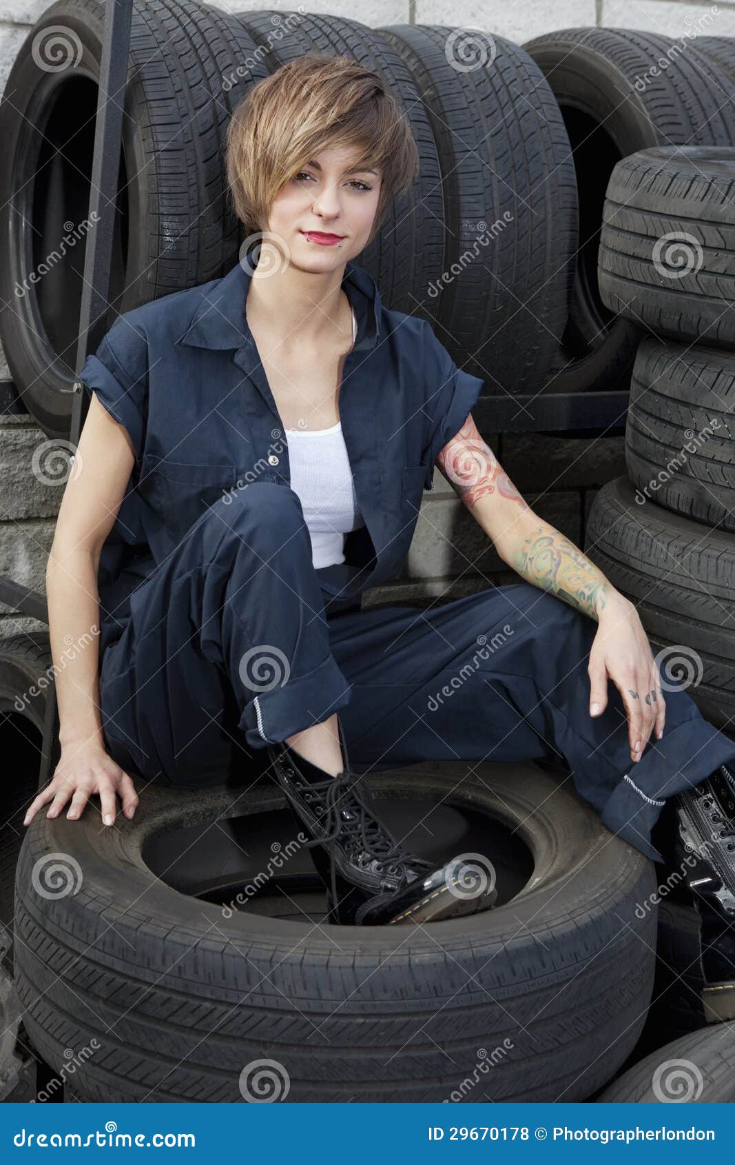 Portrait of a Young Mechanic Sitting on Tires in Car Workshop Stock ...
