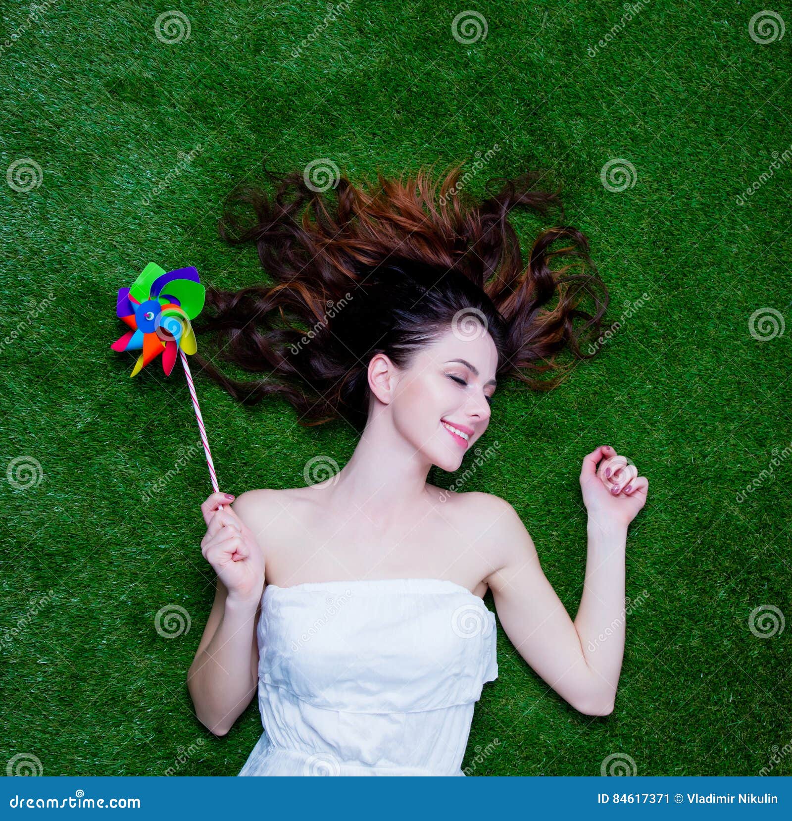 Portrait Of A Young Redhead Woman With Pinwheel Lying Down On Gr Stock